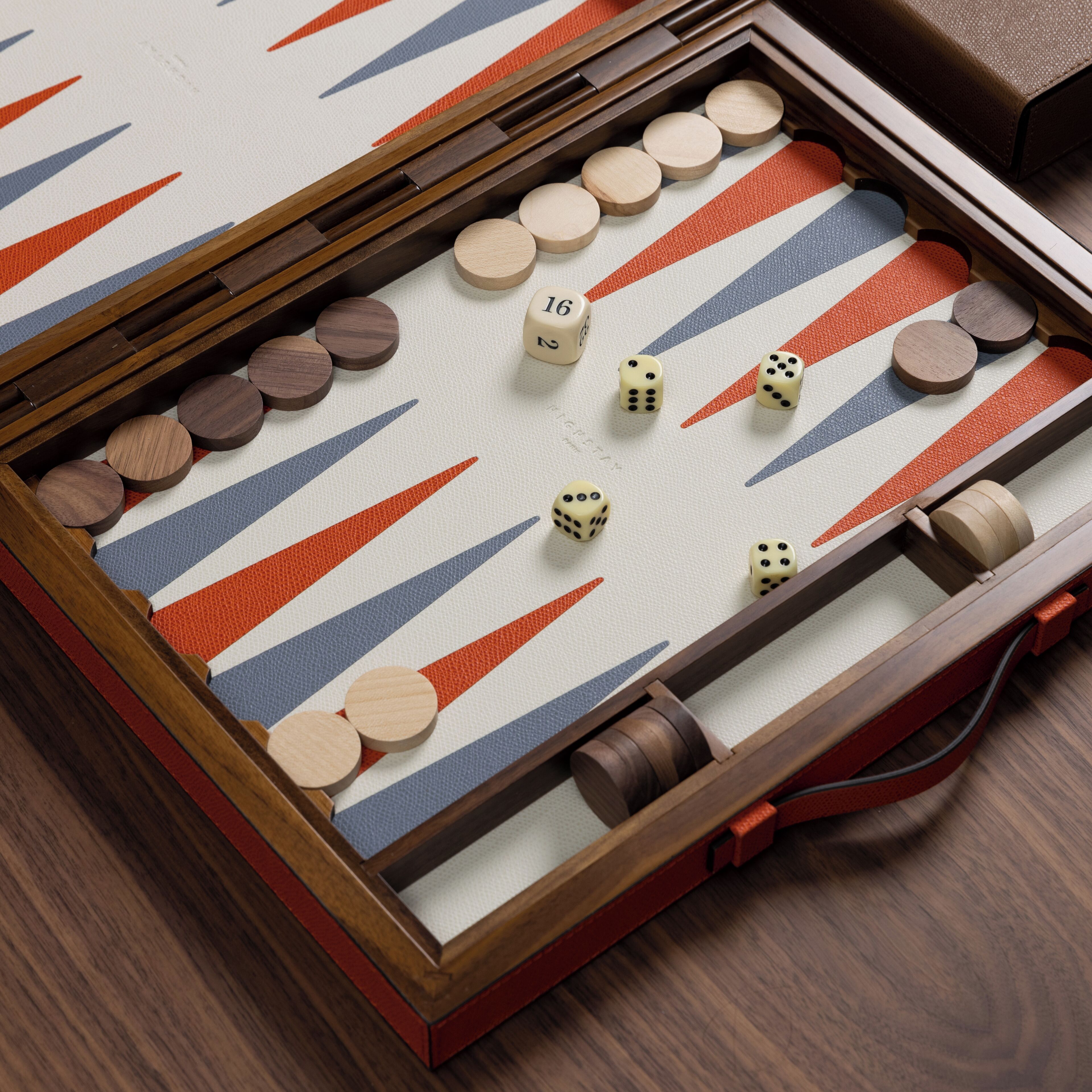 Um jogo de gamão com peças de madeira e dados sobre um tecido riscado.
