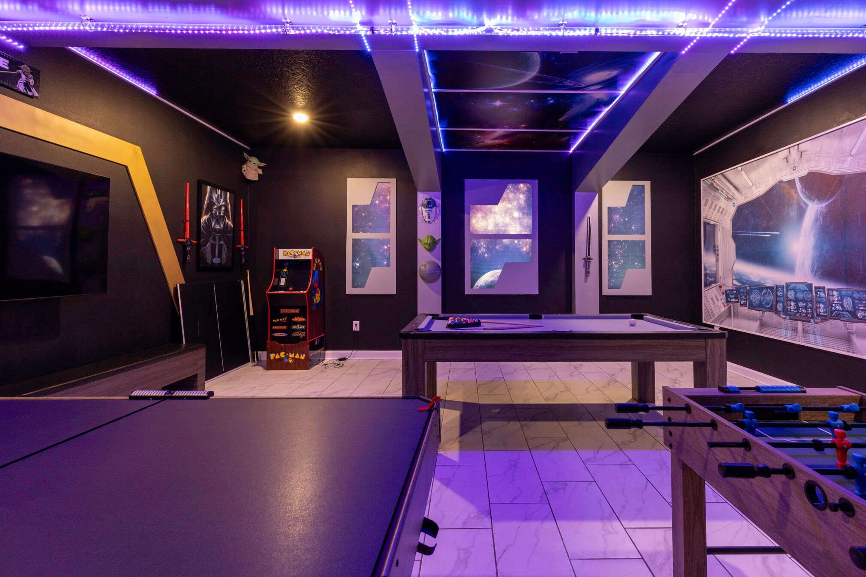 Quarto com mesa de bilhar, mesa de futebol e console de jogos.