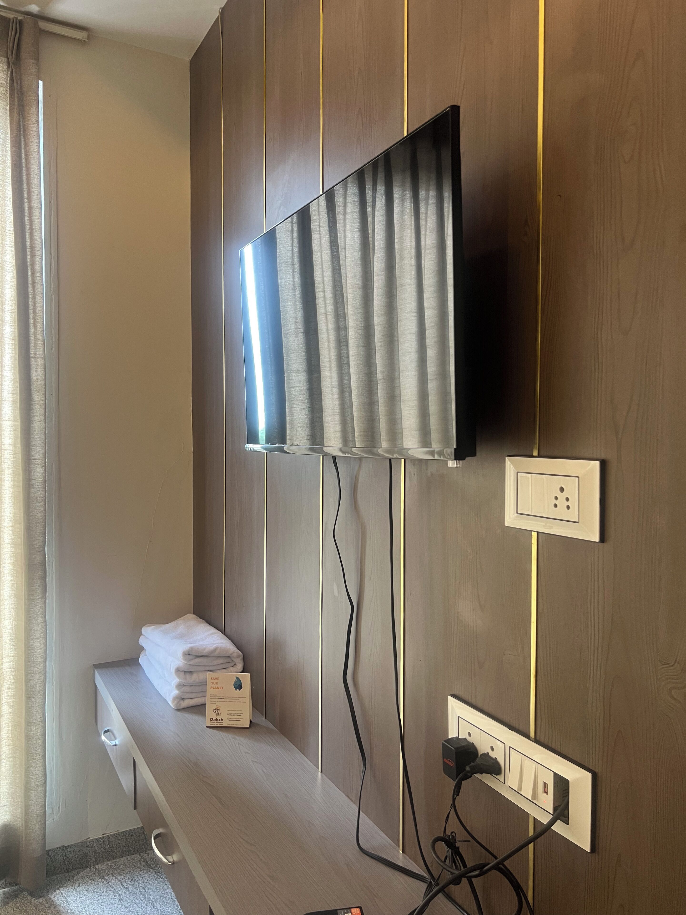 Uma casa de banho moderna com uma toucador de madeira, uma televisão montada e um dispensador de toalhas.