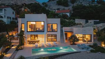 Uma casa moderna de dois andares com piscina, área de estar ao ar livre e vista para a paisagem circundante.