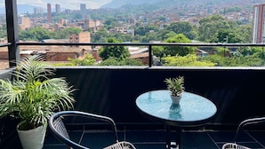 Uma varanda com vista para a paisagem urbana, incluindo edifícios e vegetação.
