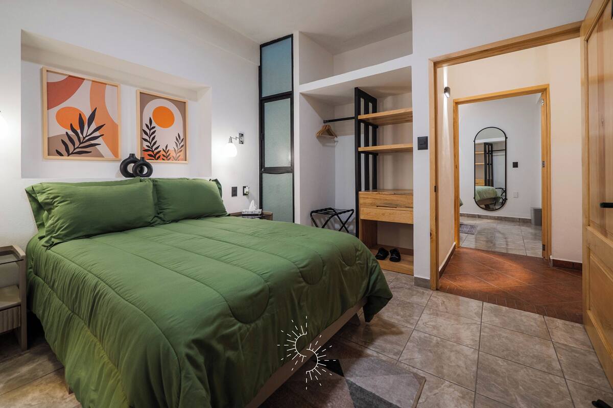 Quarto moderno com cama verde, escrivaninha e closet espaçoso.