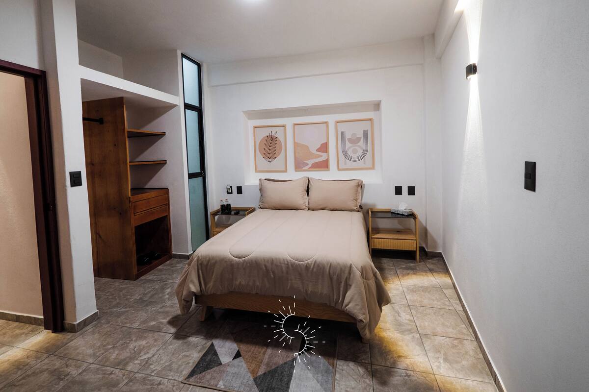Quarto com cama, mesa de cabeceira, guarda-roupa de madeira e porta que dá para uma escada.
