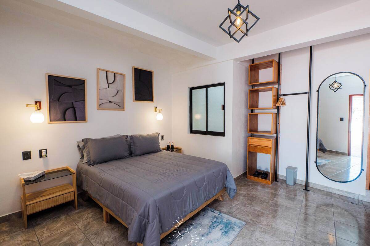 Quarto moderno com cama grande, mesas de cabeceira, guarda-roupa embutido e espelho.