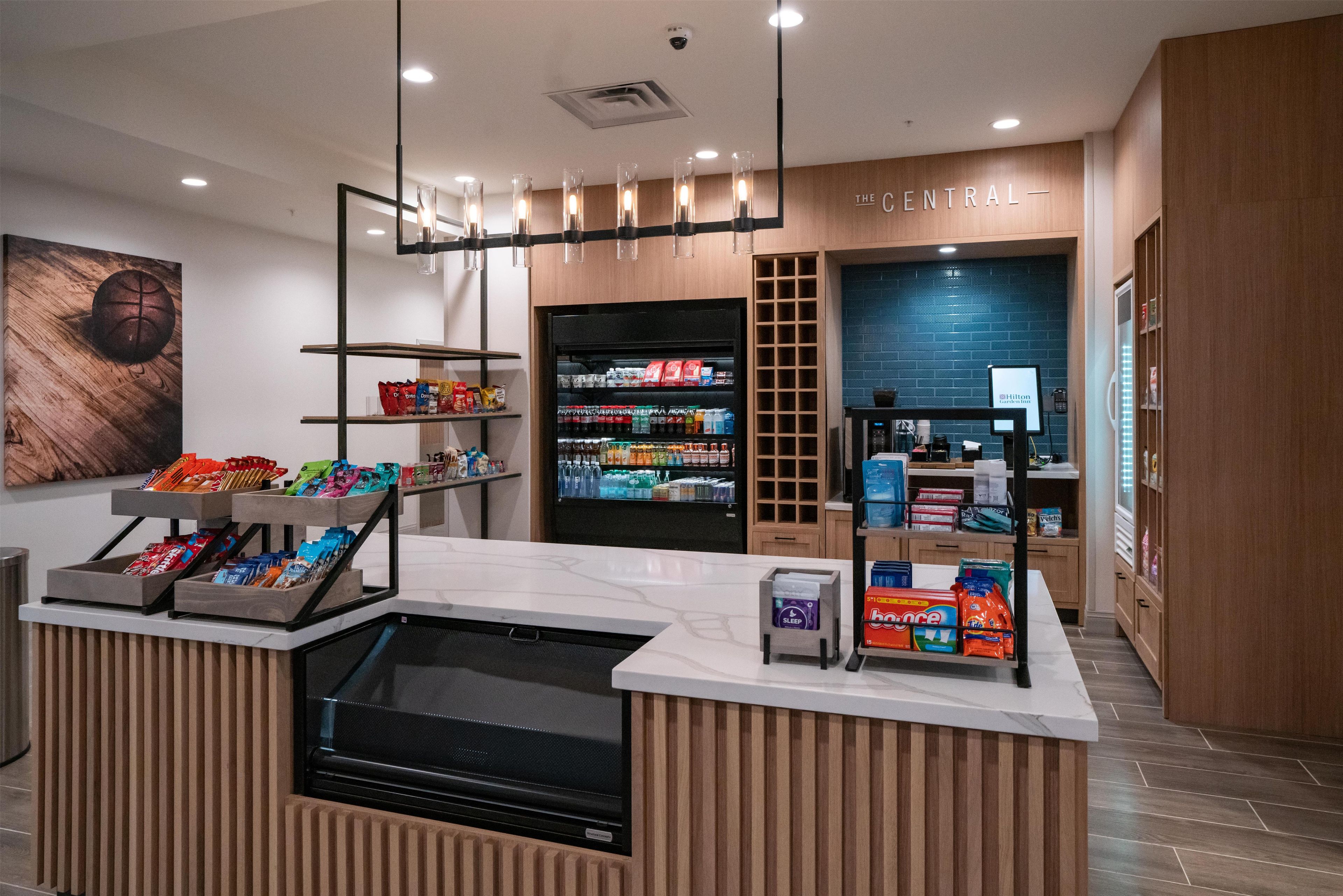 Um hall de hotel com um balcão central, máquinas de venda automática e uma área de estar.