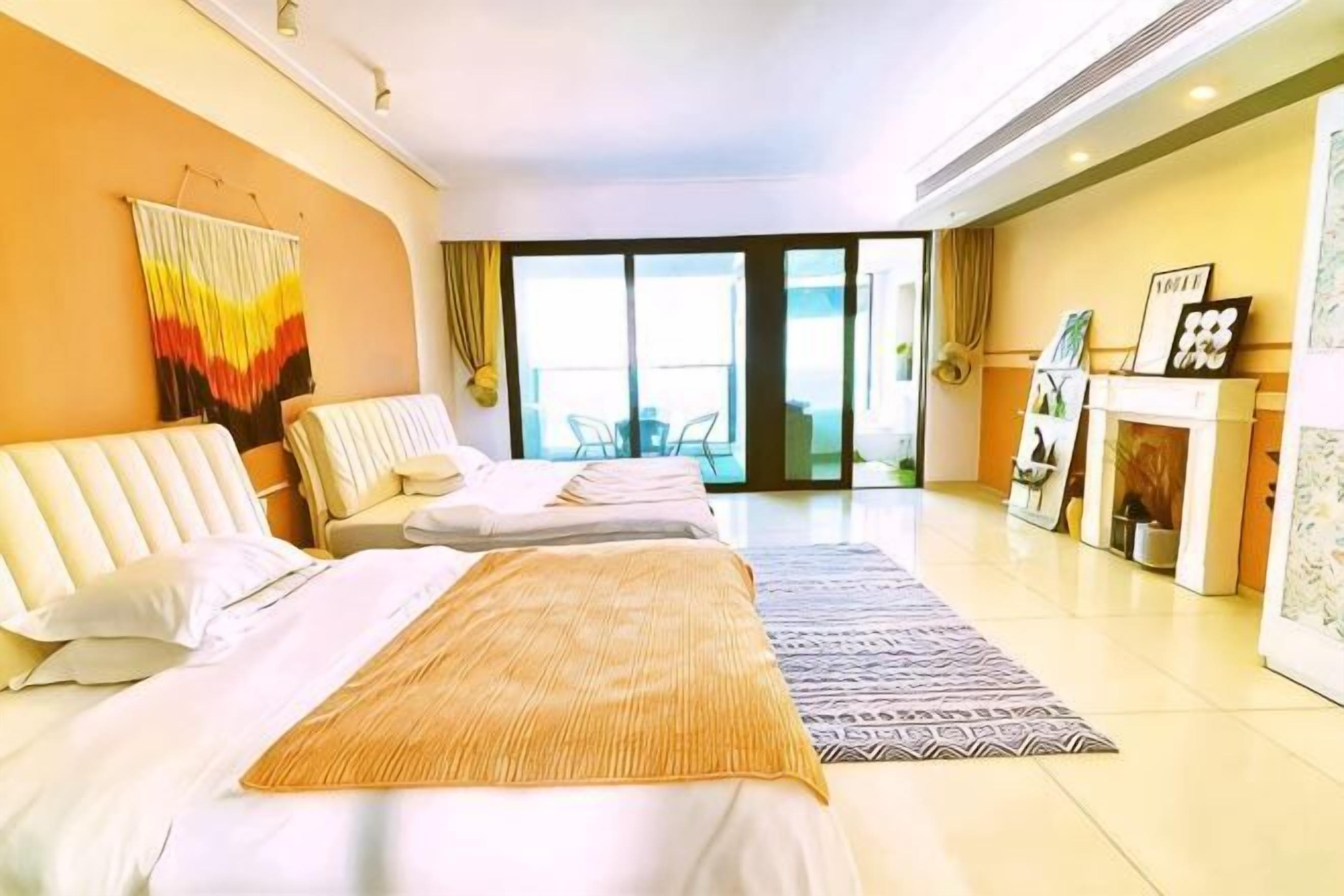 Quarto de hotel com uma cama grande, duas poltronas, um sofá, lareira e uma varanda com vista.