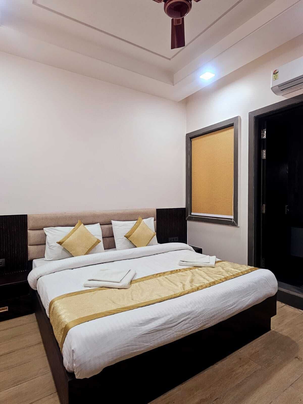 Quarto de hotel com cama grande, ventilador de teto e ar condicionado, e uma porta.