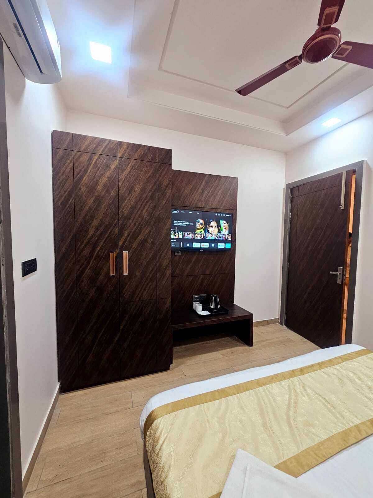 Quarto com cama, guarda-roupa, televisão e ventoinha no teto.