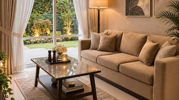 Sala de estar moderna com sofá, mesa de centro e vista para um jardim através de uma porta de vidro.