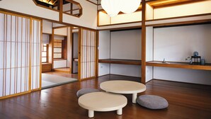 Um quarto japonês tradicional com tatames, biombos shoji e uma mesa de madeira baixa com almofadas.