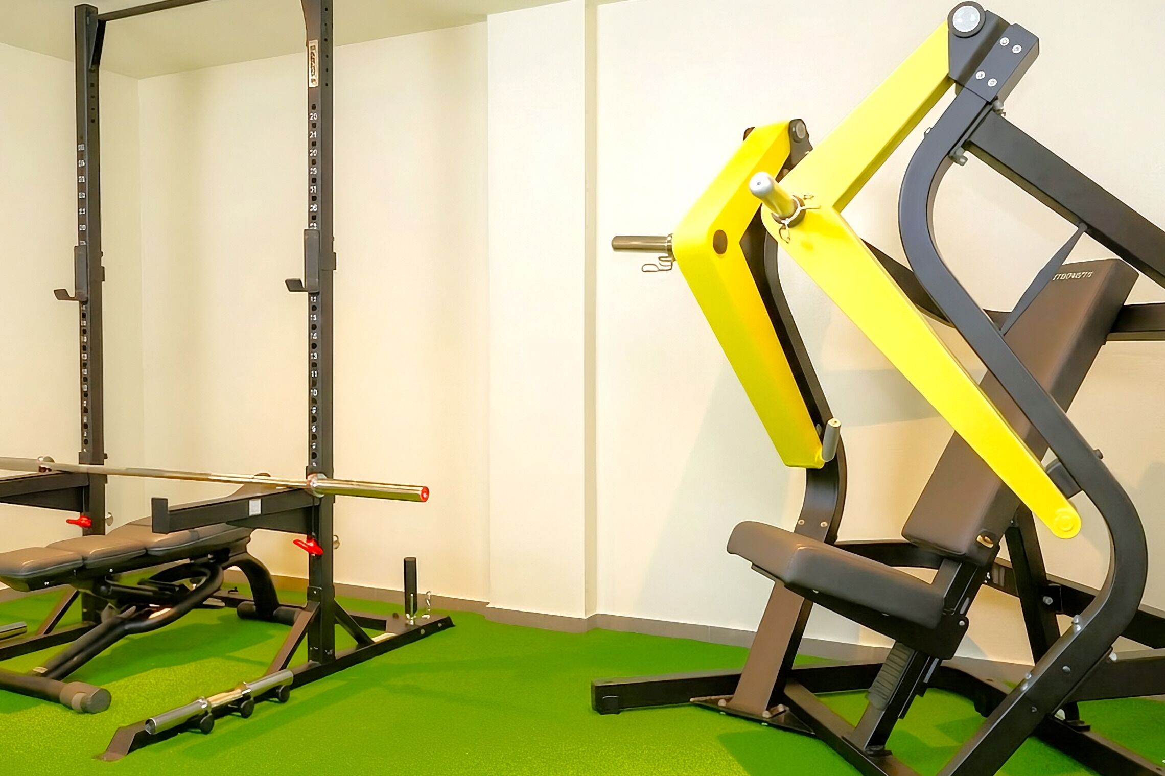Uma academia com equipamentos de musculação, um banco e uma estrutura para agachamento.