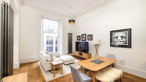 Uma sala de estar moderna com um sofá, uma mesa de jantar e uma TV.