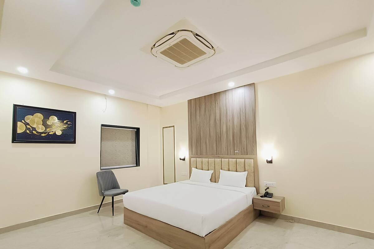 Quarto moderno com uma cama grande, uma cadeira, uma mesa de cabeceira e um respiradouro no teto.