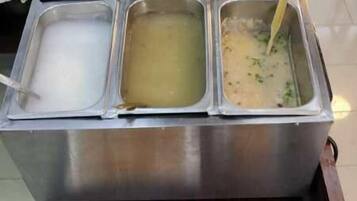 Buffet com diversos pratos, incluindo frituras, um prato branco com um prato em camadas e uma bandeja com frituras.