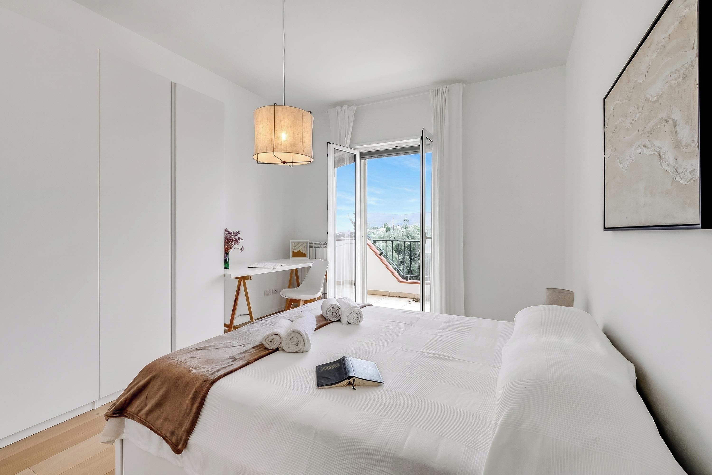 Quarto moderno com uma cama grande, uma escrivaninha e vista para o exterior.