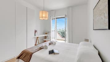Quarto moderno com uma cama grande, uma escrivaninha e vista para o exterior.
