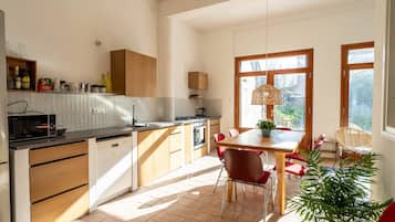 Uma cozinha moderna com armários de madeira, máquina de lavar louça embutida e área de refeições com mesa e cadeiras.