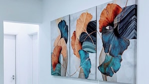Um corredor com chão em mosaico e uma obra de arte na parede com motivos florais abstratos.