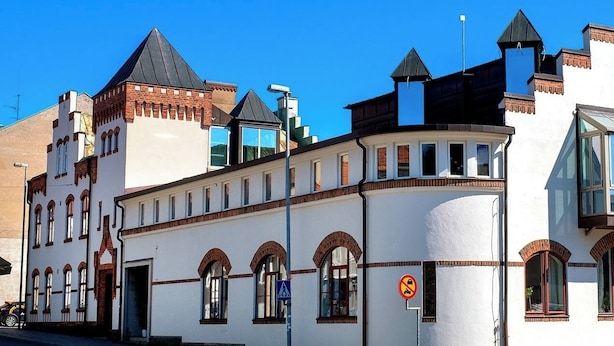 Um edifício histórico com janelas em arco, uma torre e uma entrada com portão.