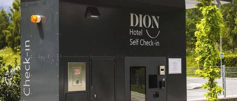 Quiosque de auto check-in para o Hotel DION, com teclado, pequena tela e porta.