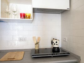 Uma cozinha com fogão moderno, tábua de corte e descanso para panelas.