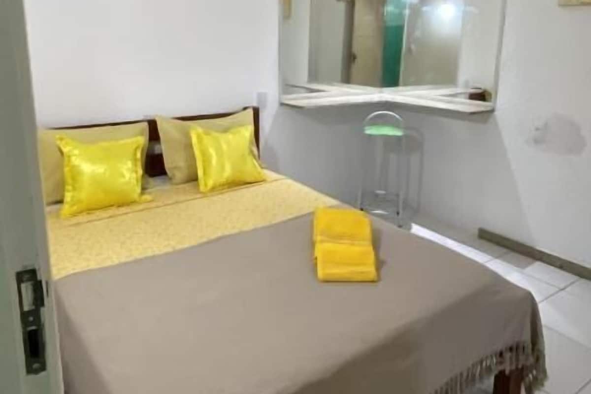 Um quarto com uma cama, um espelho e um objeto amarelo sobre a cama.