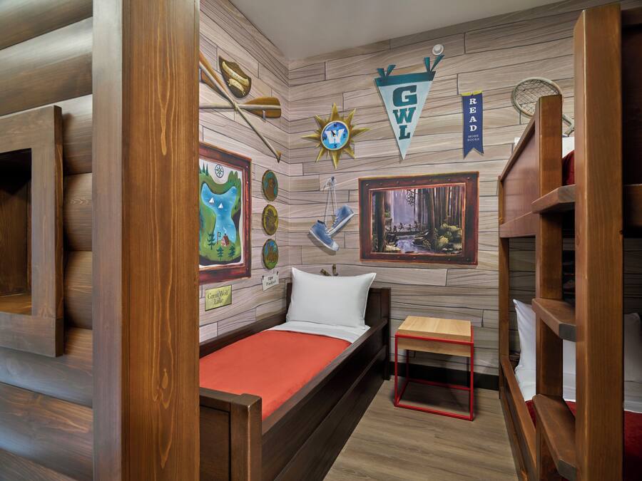 Quarto no estilo de cabana com uma cama, uma mesa pequena e uma beliche.