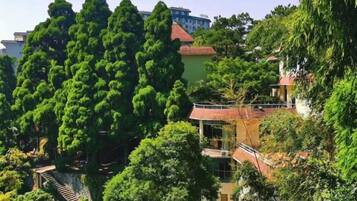 Um edifício com telhado vermelho, cercado por árvores verdes densas.