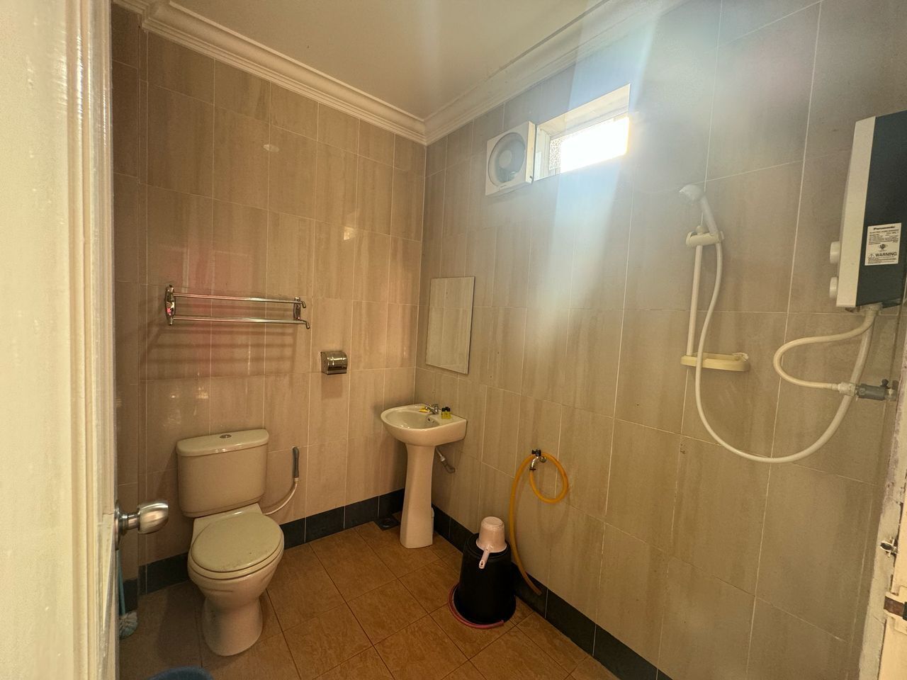 Casa de banho com sanita, lavatório e chuveiro.