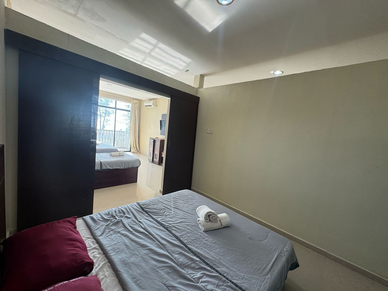 Quarto com uma cama, uma janela e uma porta que dá para outro cômodo.