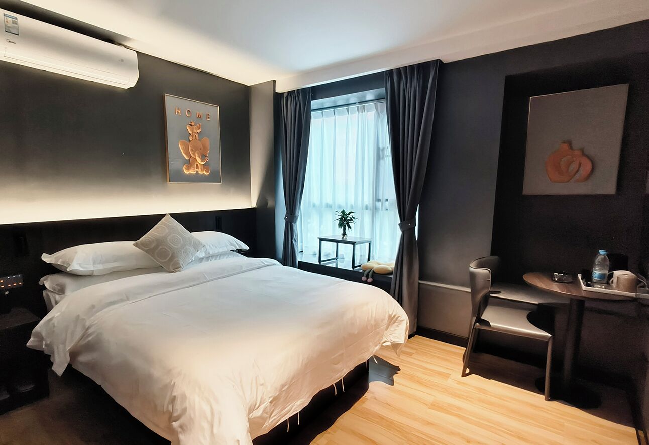 Quarto de hotel moderno com uma cama grande, uma mesa pequena e uma cadeira.