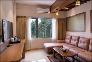 Uma sala de estar moderna com sofá, mesa de centro, televisão e janela com cortinas.