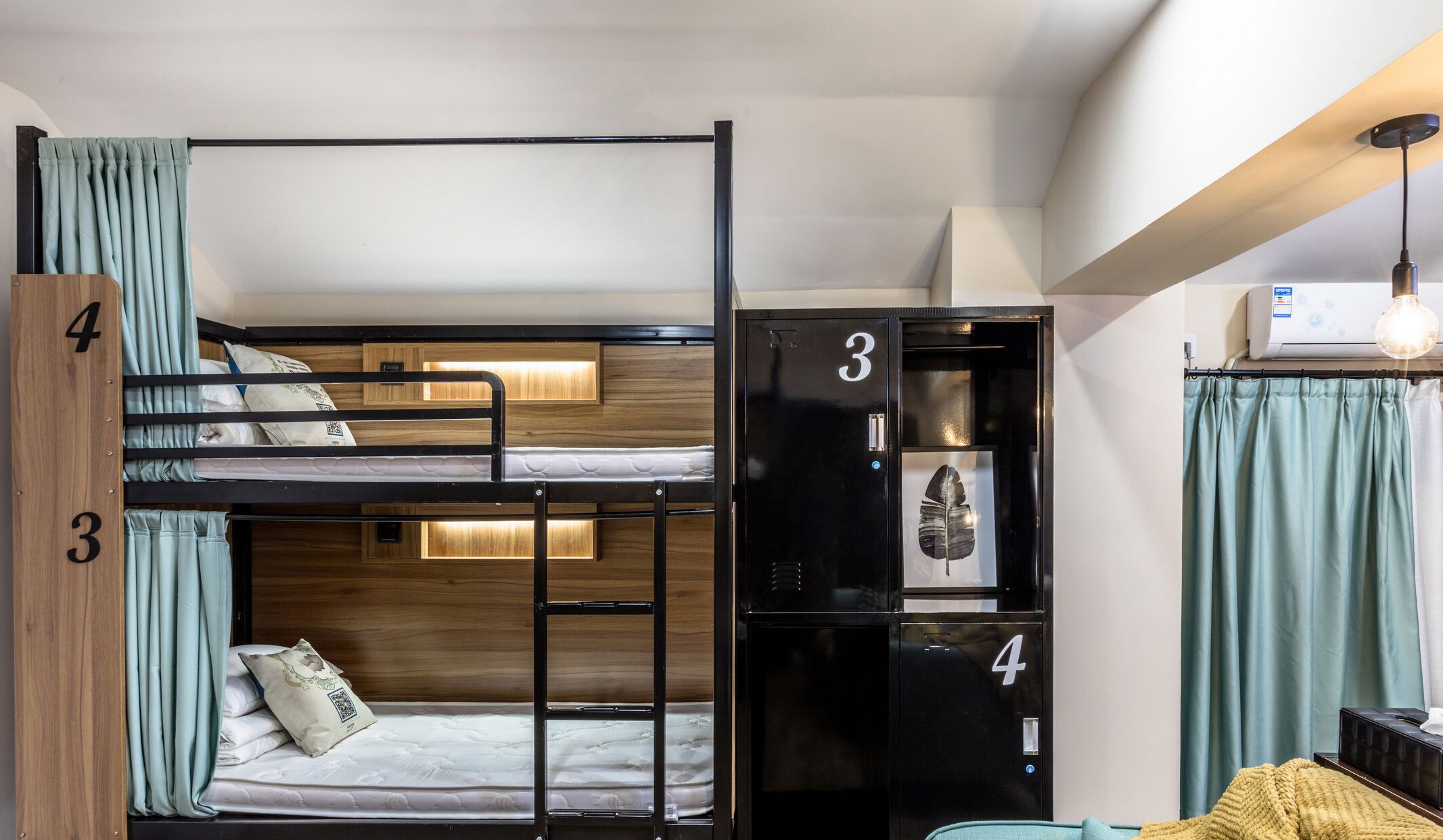 Quarto com beliche, um armário de madeira, um painel com número e um ventilador de teto.