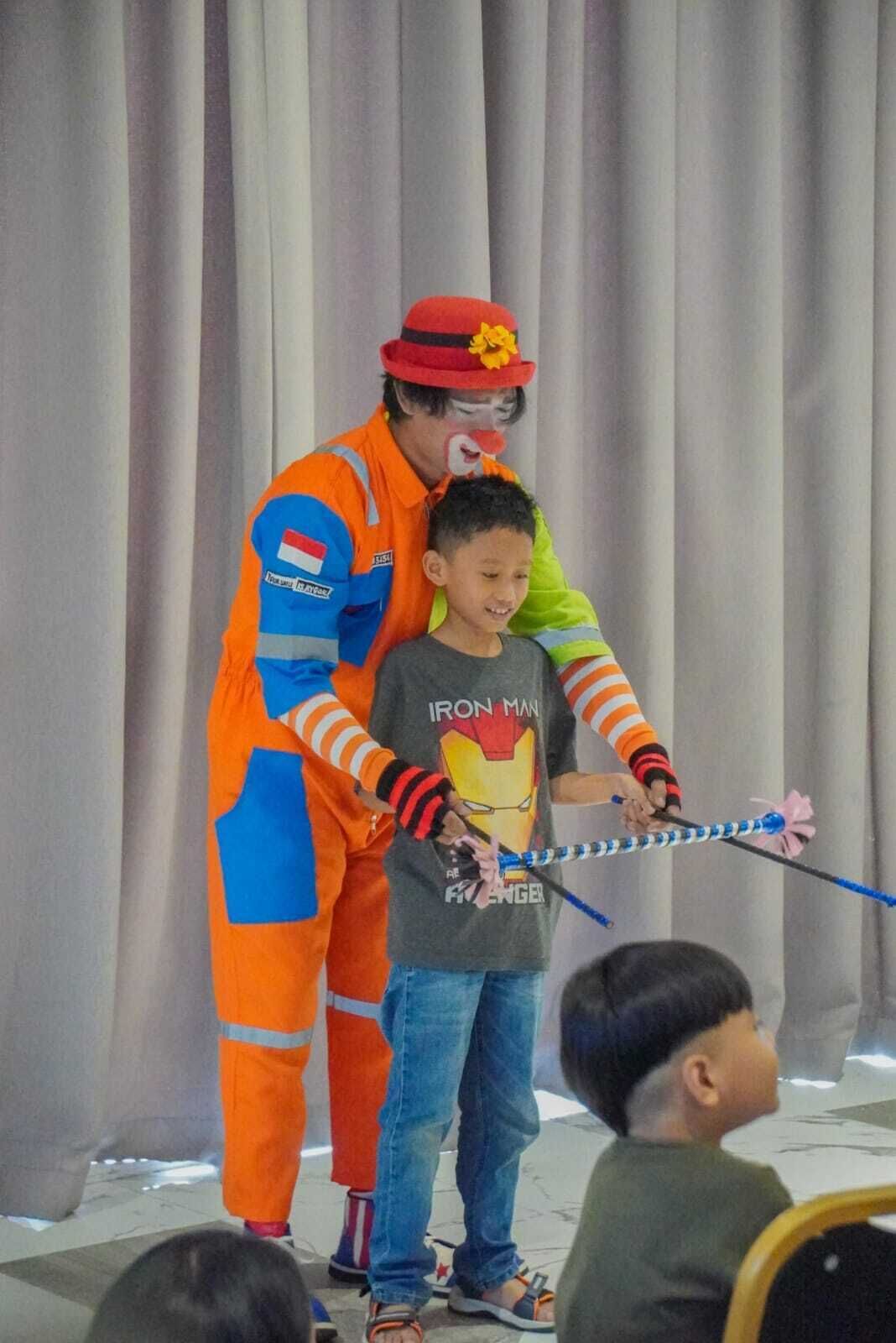 Uma pessoa vestida de palhaço ao lado de uma criança segurando um brinquedo.