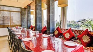 Uma sala de jantar com uma mesa comprida posta para refeição, grandes janelas e vista para a cidade.