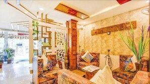 Um saguão de hotel com área de estar, sofás estampados e uma mesa de centro.