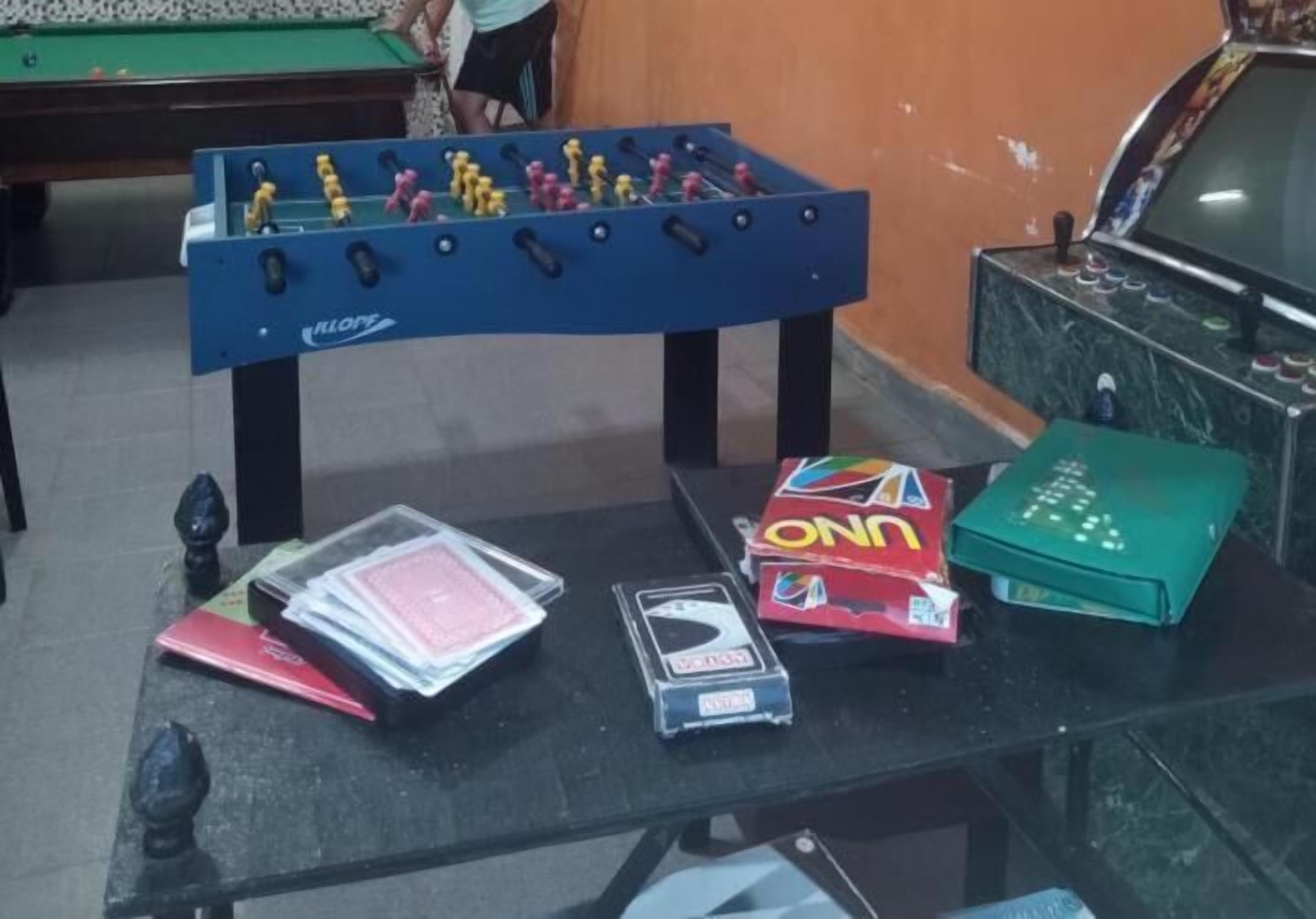 Uma mesa de futebol de mesa, uma mesa de bilhar e uma máquina de jogos numa sala com uma mesa de vidro.