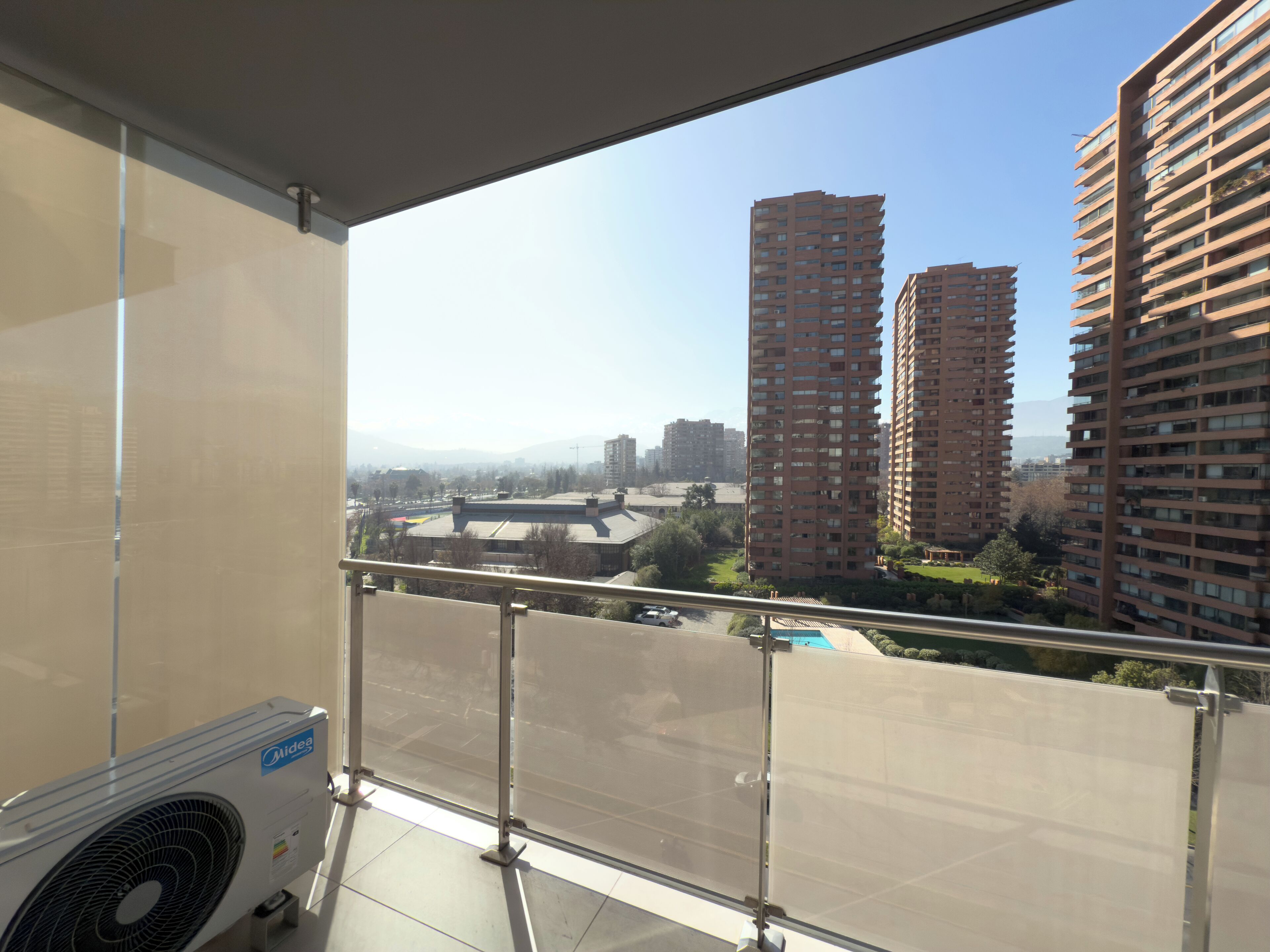 Varanda com vista para edifícios altos, um ventilador e céu claro.
