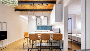 Uma cozinha moderna com uma ilha central, quatro banquetas de bar e uma mesa de jantar.