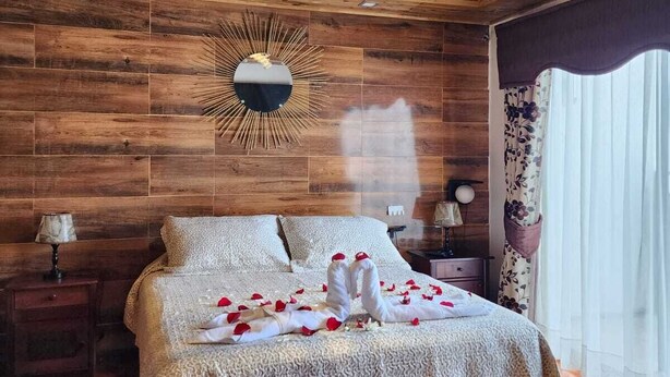 Quarto com painéis de madeira, uma cama, um candelabro e um espelho na parede.