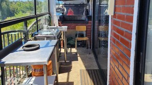 Uma área de cozinha externa com forno de tijolos, uma mesa e uma lixeira.