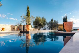 Piscina com água cristalina refletindo árvores e céu ao redor.