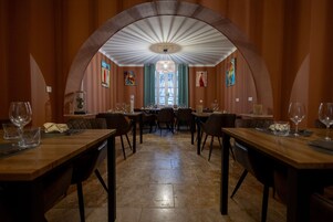 Uma sala de jantar com teto alto abobadado, um candelabro e obras de arte nas paredes.