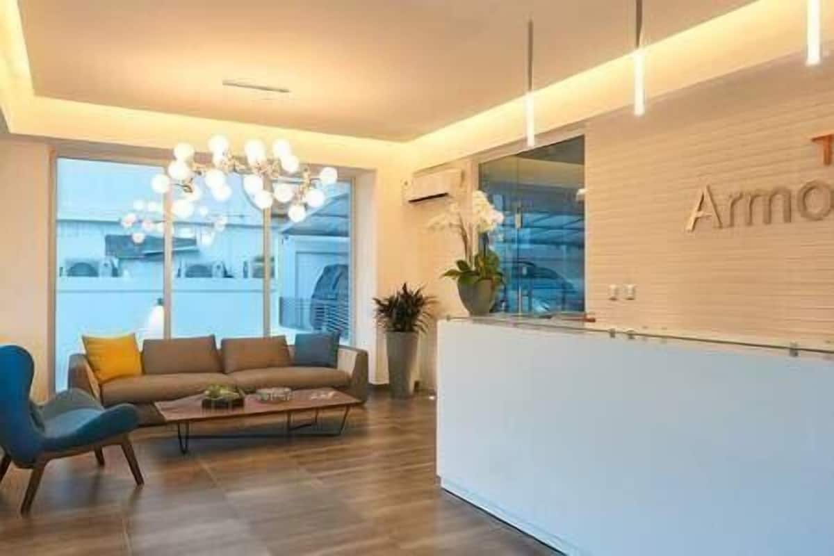 Uma área de recepção moderna com sofá, cadeiras, mesa de centro e um lustre.