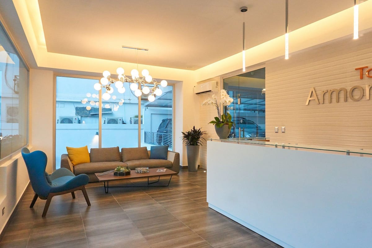 Uma área de recepção moderna com sofá, cadeiras, mesa de centro e um lustre.