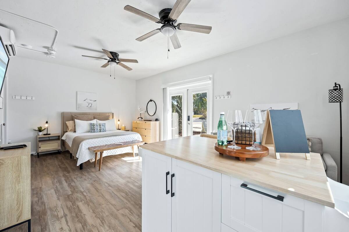 Quarto moderno com cama, mesas de cabeceira, um ventoinha no teto e janela com vista para o exterior.