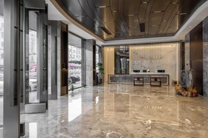 Um lobby moderno com piso de mármore, balcão de recepção e uma grande janela.
