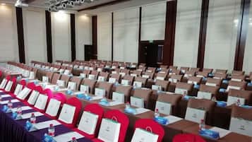 Sala de conferência com fileiras de cadeiras, placas de identificação e garrafas de água.