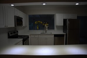 Um frigorífico, um micro-ondas, um forno, utensílios de cozinha 