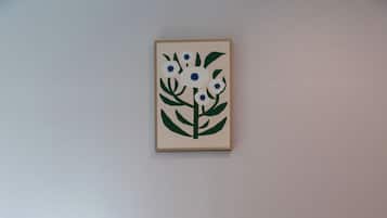 Quarto de hotel com duas camas, mesa de cabeceira com abajur e uma obra de arte pendurada na parede.